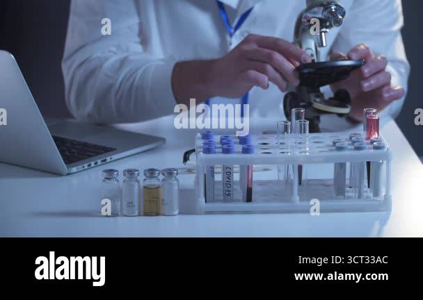 Scientist in lab coat and eyeglasses working at workplace with laptop ...