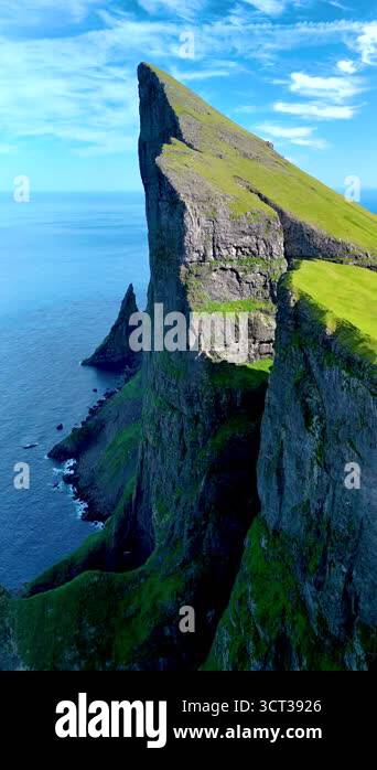 Vast cliffs tower over the deep blue waters of the Atlantic Ocean in a ...