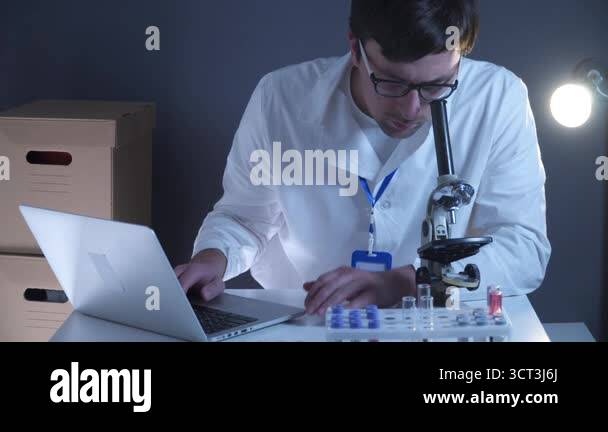 Scientist at workspace in laboratory with microscope, computer, and ...