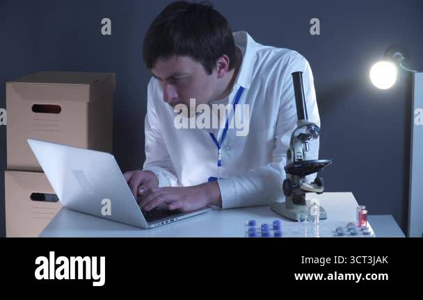 Scientist at workspace in laboratory with microscope, computer, and ...