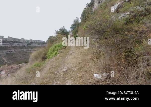 Point of view walking a narrow mountain trail on the edge of a cliff ...