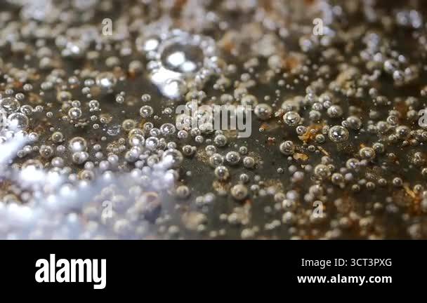 Oil bubbles rise in a pot as food is being prepared in the kitchen ...