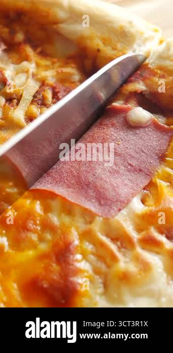 Thin meat is being sliced on a hot, cheesy dish, creating a tasty mix ...