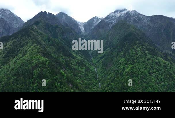 deep mountain valley with a waterfall cascading down, surrounded by ...