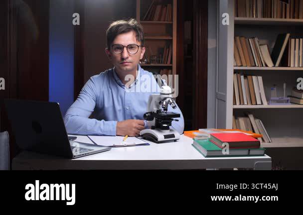 portrait of a Young scientist sitting at desk with microscope, laptop ...