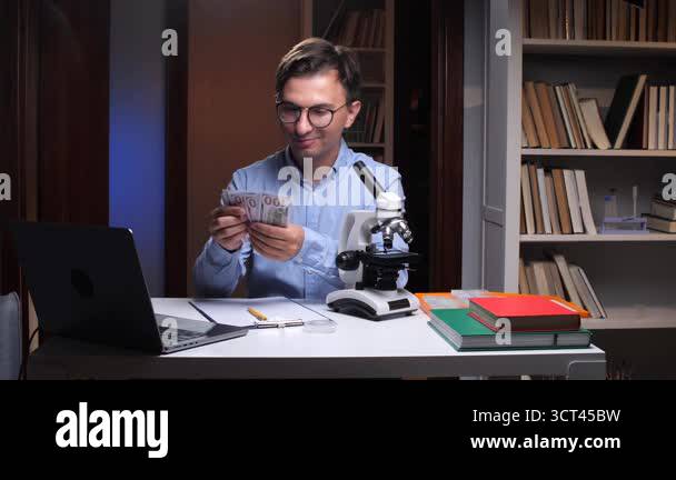 Young scientist counting money usd banknotes sitting at desk in his ...
