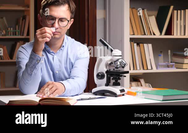 Close-up portrait young male scientist wearing glasses, smelling a ...