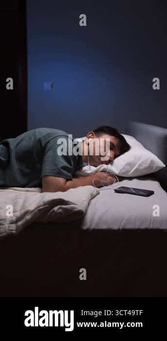vertical video Young man sleeping peacefully in bed at night while ...