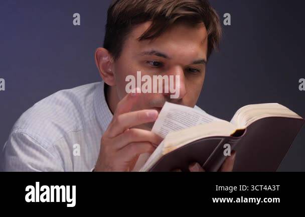 Man holding an open book, intently reading and concentrating on the ...