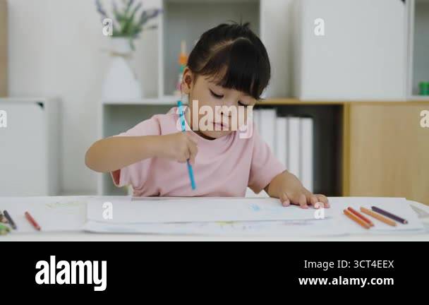 toddler baby girl training to drawing with colored pencil on a desk at ...