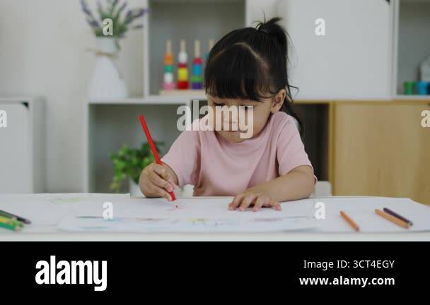 toddler baby girl training to drawing with colored pencil on a desk at ...