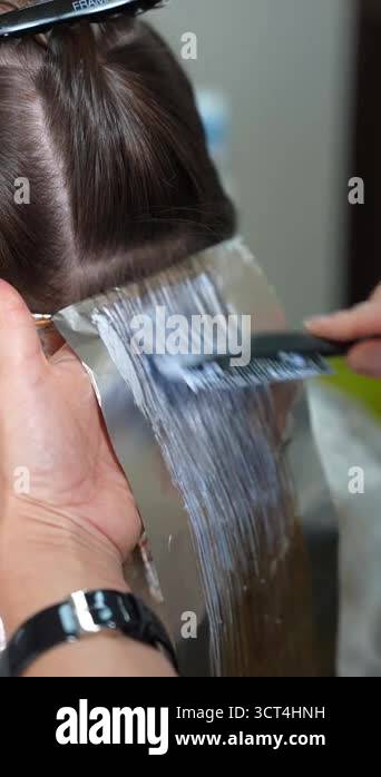 Close-up of hair lightening process. Hair strands placed on foil with ...