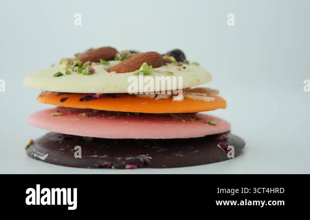 Stacked layers of colorful chocolate discs topped with nuts and fruits ...