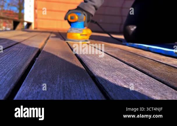 A person works on sanding a wooden deck, focusing on refinishing the ...
