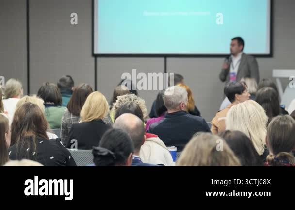 Presenter speaks to large audience during seminar in modern conference ...