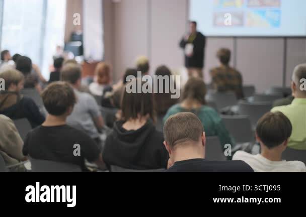 Professional setting featuring speaker delivering presentation to ...