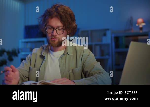Young Man Reads Book with Deep Focus in Evening Study Environment ...