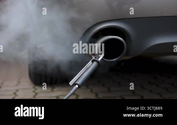 Car exhaust pipe emits dense smoke during emission test on city ...