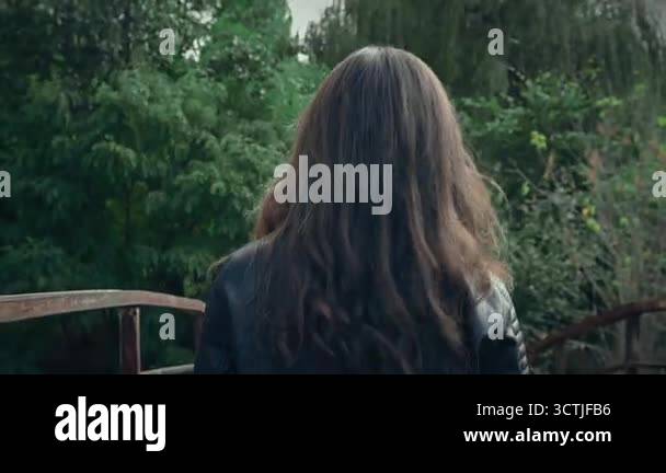Back shot sad young woman going and looks around warily. Sad young ...