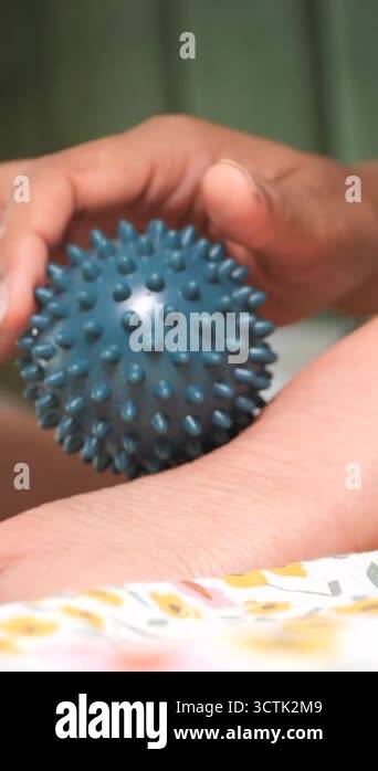 Hands apply pressure with a massage ball for stress relief and ...