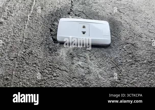 A smoking electrical outlet on a gray concrete wall from overvoltage ...
