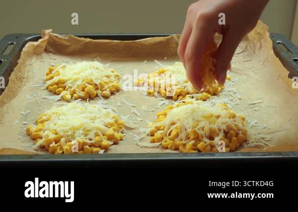 Female hands sprinkle additional grated cheddar cheese over corn ...