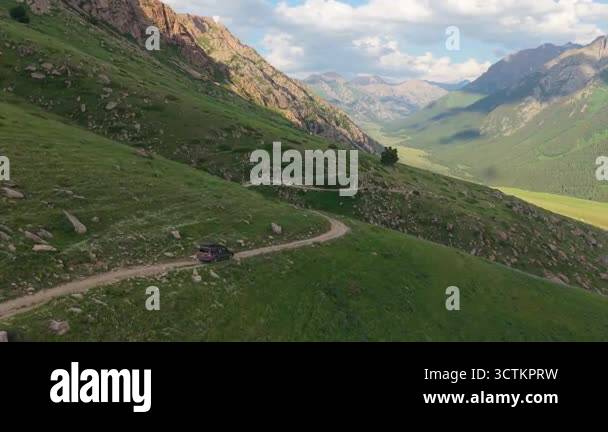 Dark colored suv carefully navigating a winding dirt road amidst lush ...