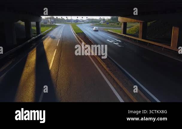 First person view of a car driving under a bridge overpass with morning ...
