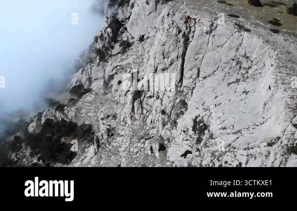 Majestic rocky mountain cliff with a narrow trail along the edge and ...