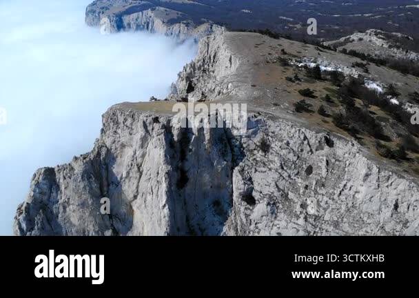 Spectacular aerial view flying over a rocky mountain cliff with a sea ...
