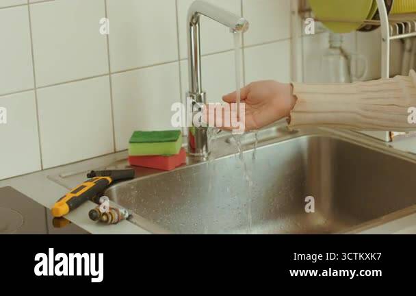Testing water flow from a chrome faucet into a stainless steel sink ...