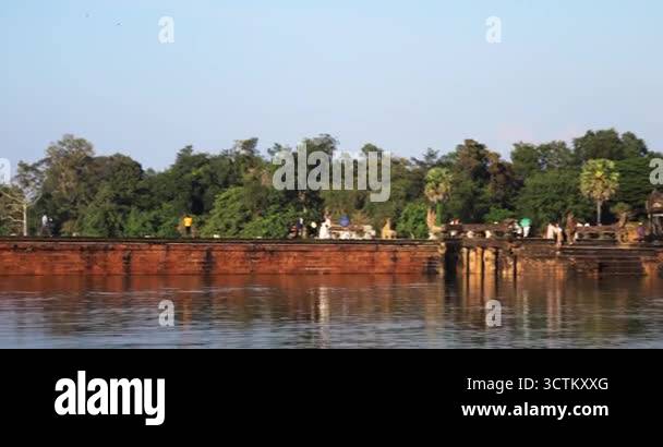 Large groups of tourists crossing bridge into Angkor Wat temple complex ...