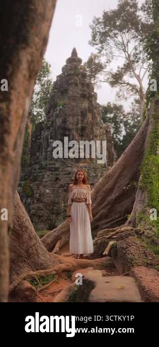 Beautiful woman in flowing white dress standing among giant tree roots ...