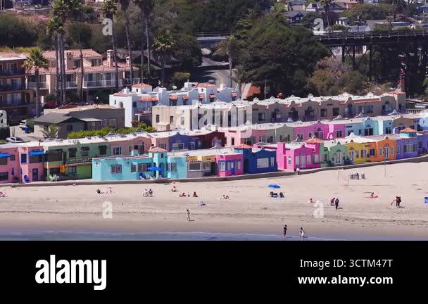Vibrant pastel buildings, a wooden trestle bridge, sandy beach, and ...