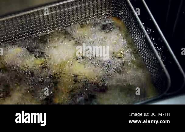 Close up of french fries is cooking into deep fryer. Crunchy potatoes ...