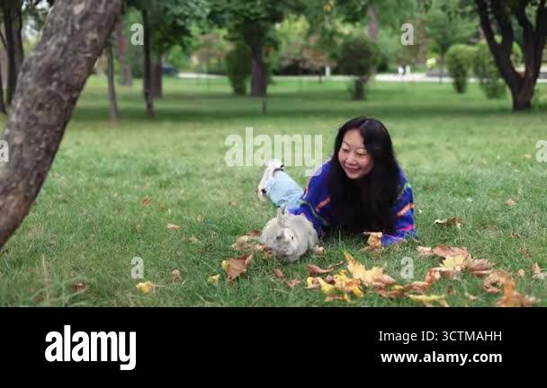 Adorable young rabbit and woman sit together outdoor in autumn forest ...