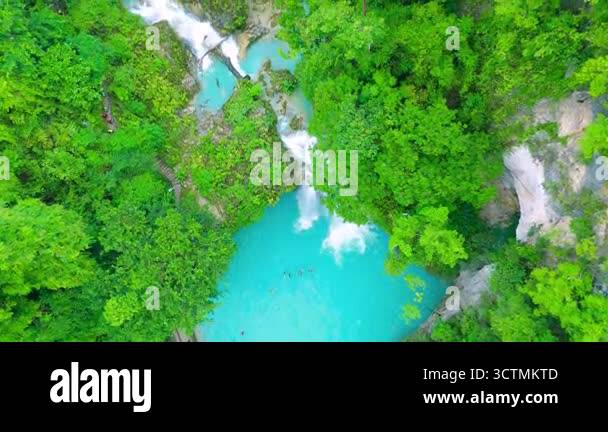 Aerial multi-tiered waterfall cascading into a turquoise pool ...