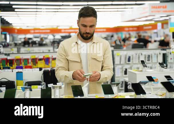 Male customer carefully comparing different smartphone models in ...