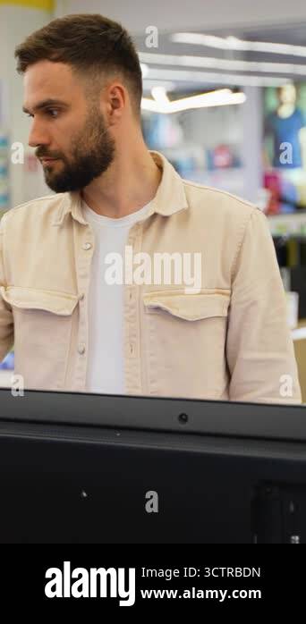 Bearded man in casual clothing using a self checkout kiosk in an ...