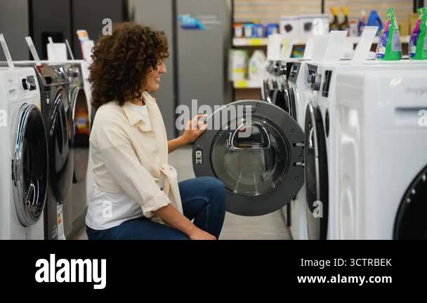 Female customer carefully examining new washing machine, gently ...