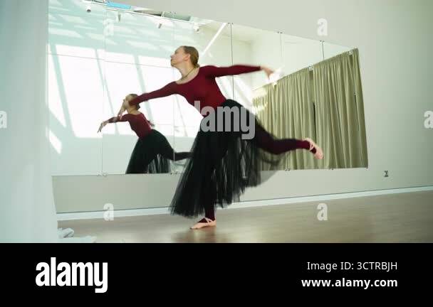 Young elegant woman in a tutu practicing ballet movements, performing a graceful dance and ...