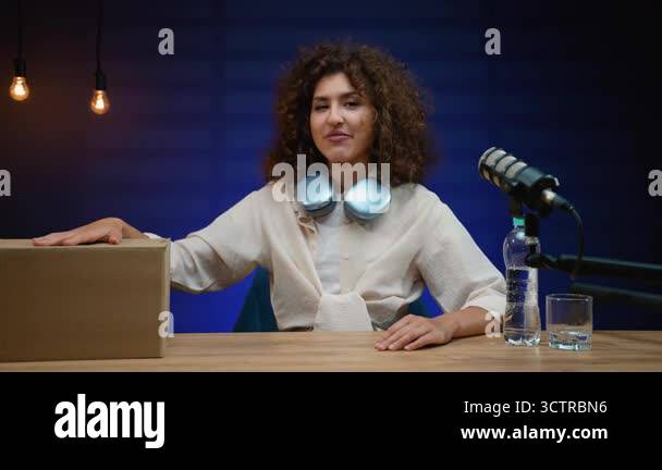 Young female blogger with curly hair live streaming, unboxing a ...