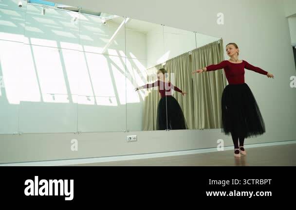Elegant young ballerina practicing classical ballet in a sunlit studio ...
