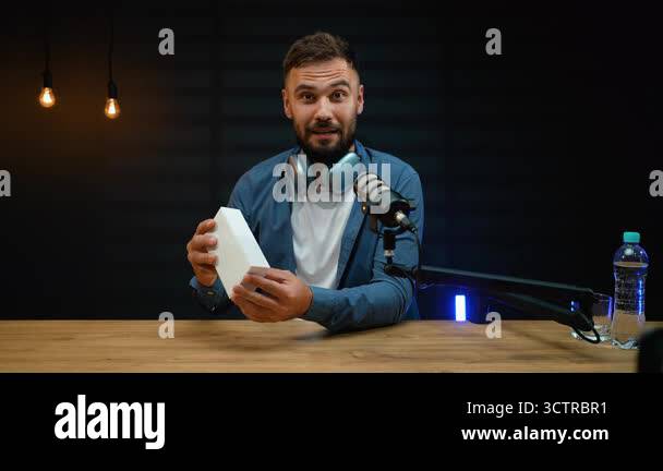 Male content creator recording a podcast and unboxing a new modern ...