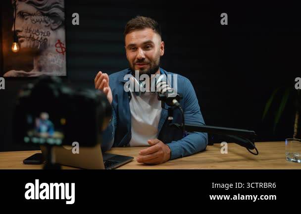 Professional male vlogger speaking into a microphone while recording a ...