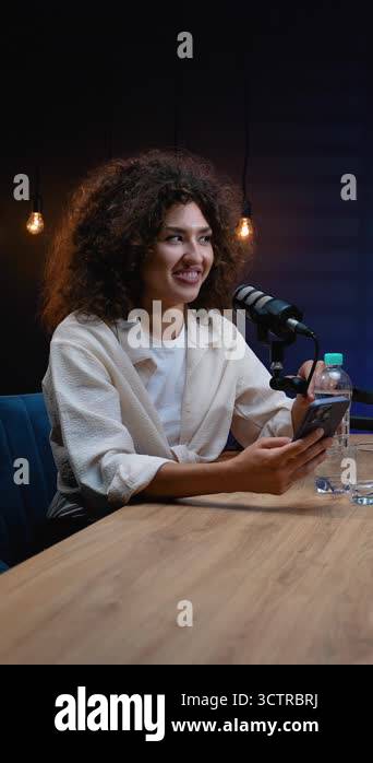 Charismatic female podcaster with curly hair speaking into a ...