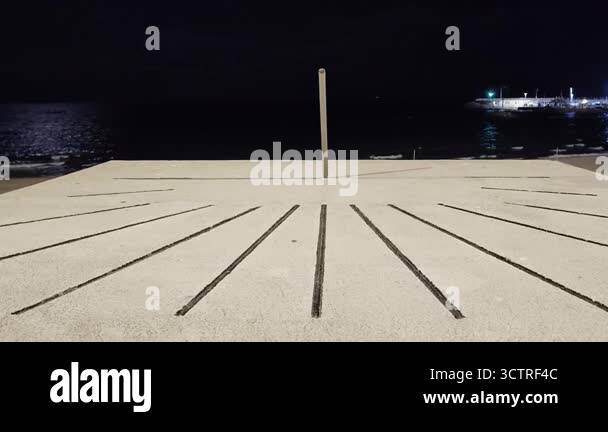 This video shows a sundial on a concrete surface by the ocean at night ...