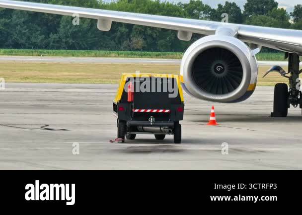 A ground support vehicle is currently servicing an aircraft engine on ...