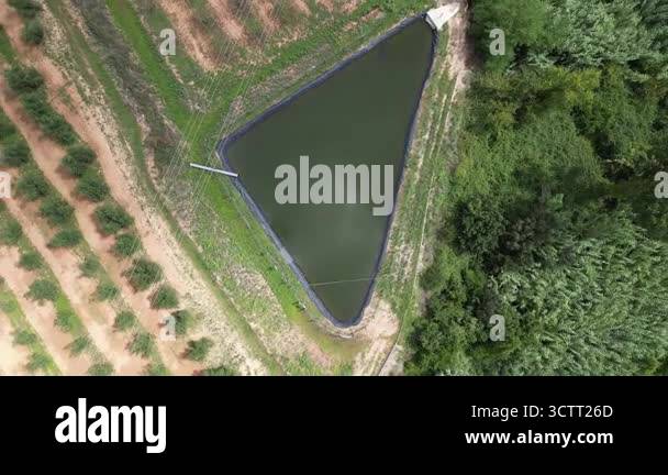 Top-down drone footage flying over a farms artificial water reservoir ...