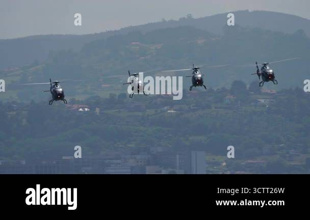 Four military helicopters flying in formation above cityscape with ...